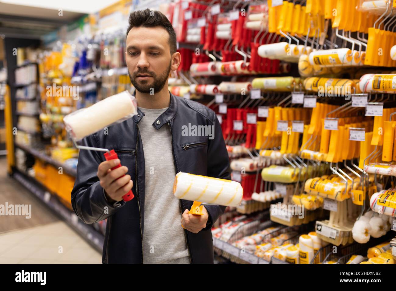 a man in a construction store picks up a roller for acrylic and oil ...