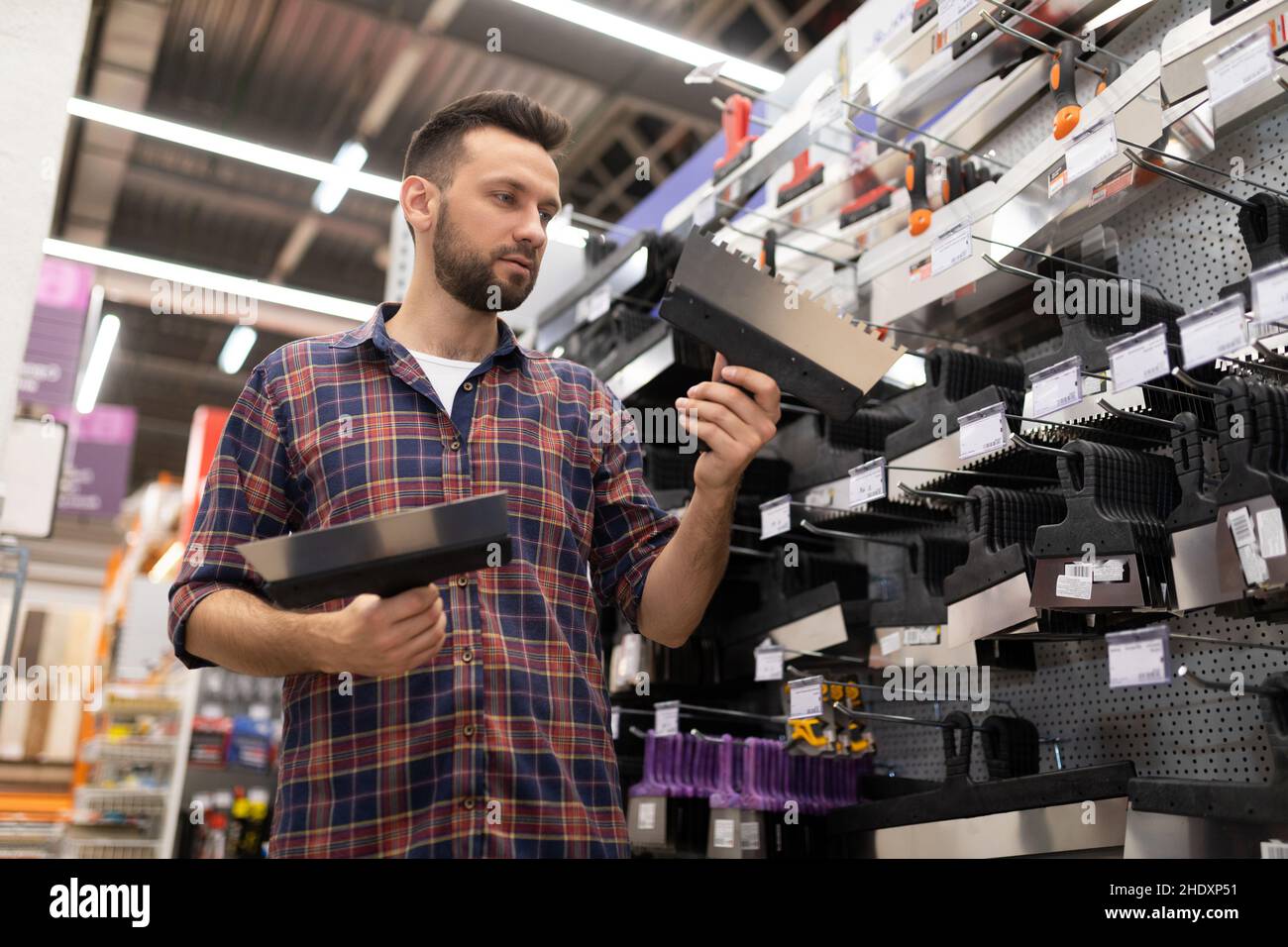 a man A builder buyer in a construction hypermarket buys spatulas for ...