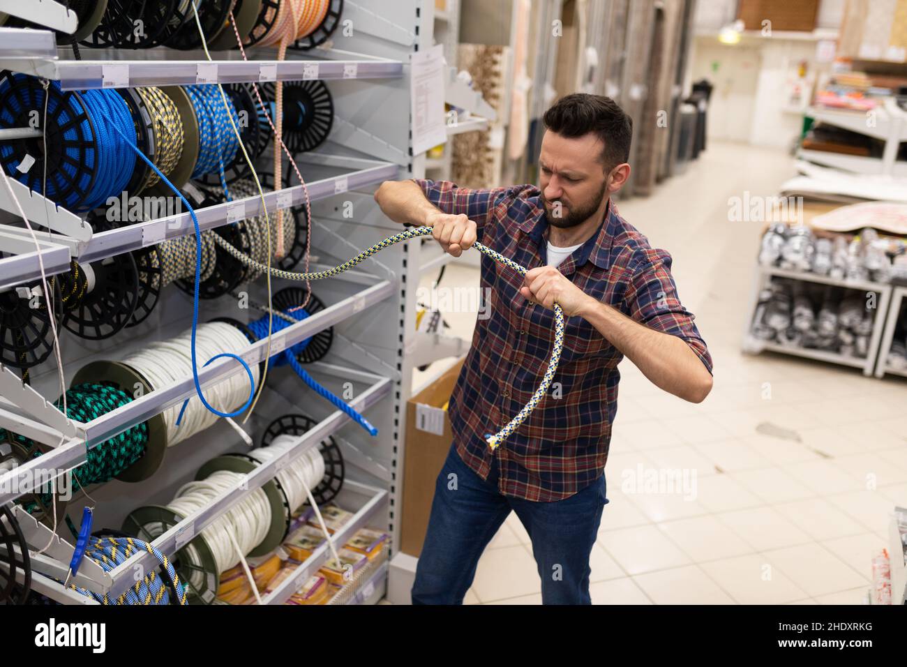 a customer in a hardware store checks the strength of a safety rope for ...