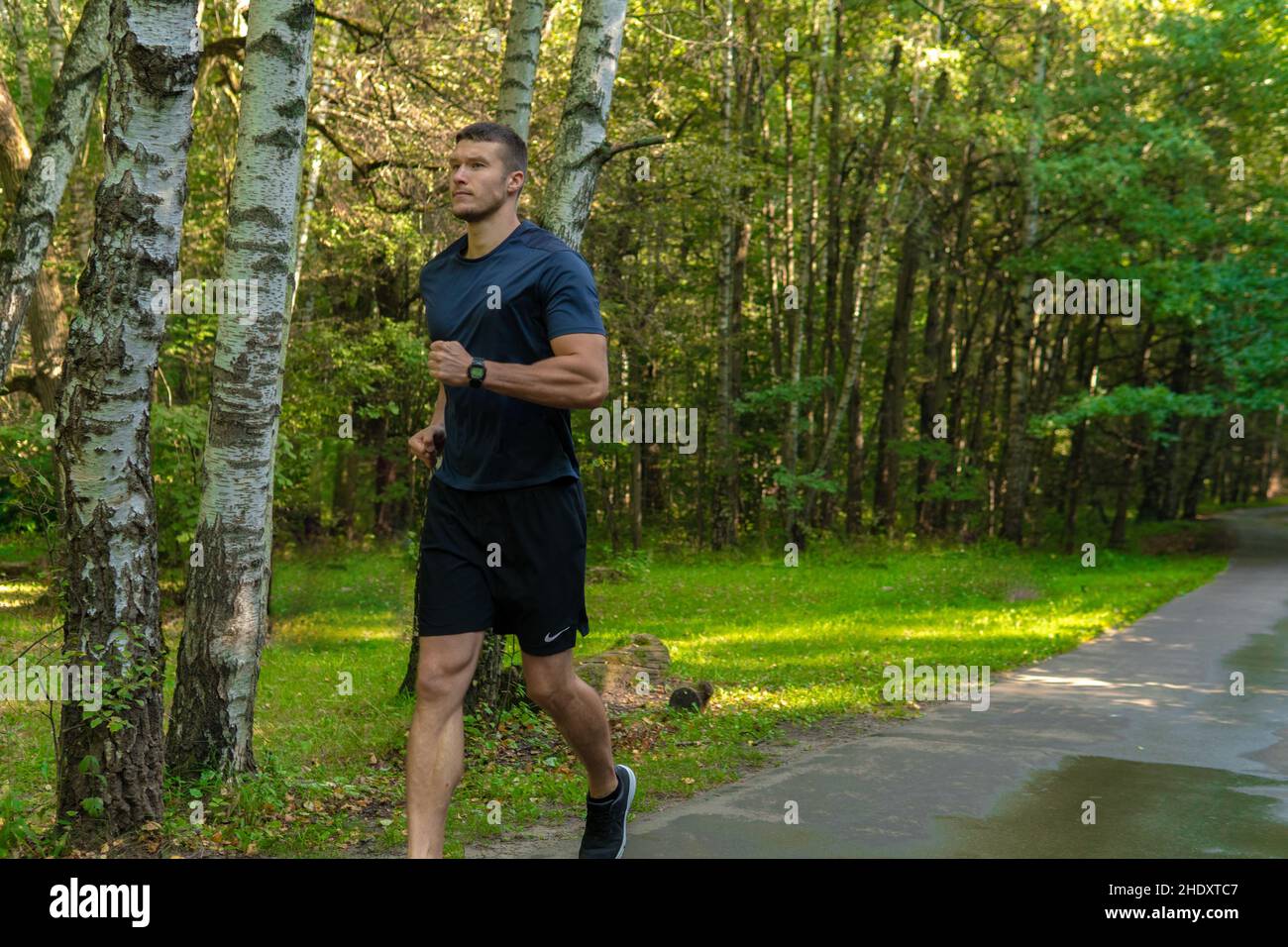A man athlete runs in the park outdoors, around the forest, oak trees ...