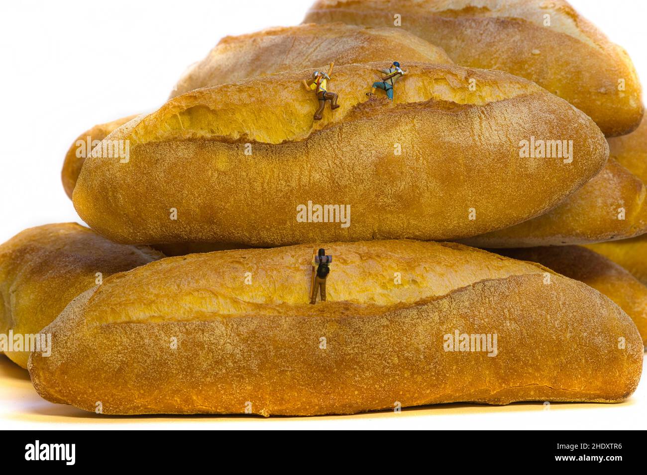 Miniature climbers climb crispy brown baked bread Stock Photo - Alamy