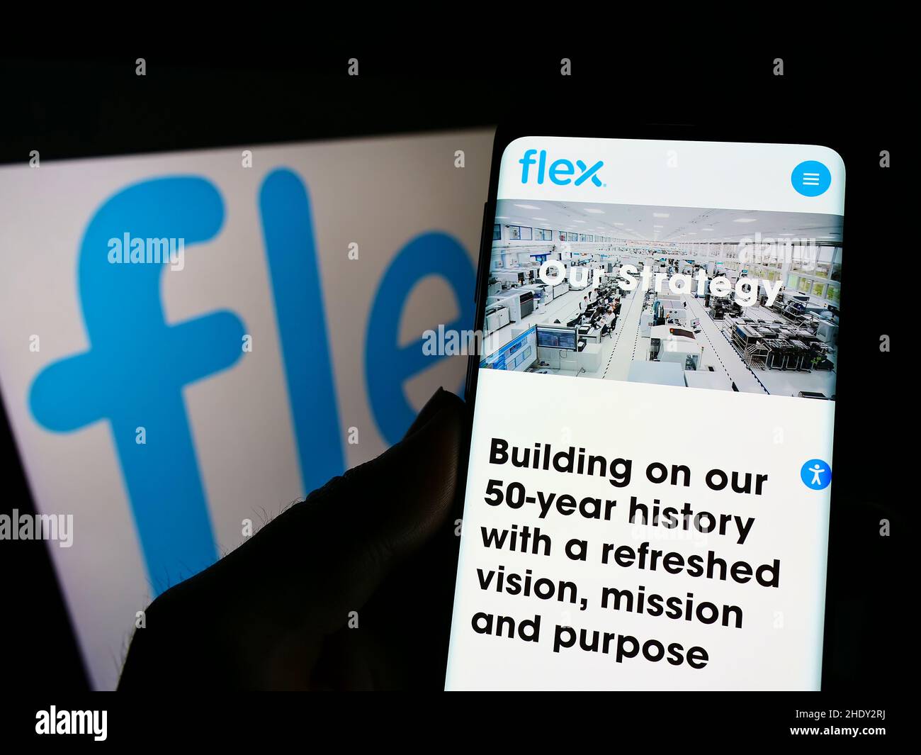 Person holding smartphone with webpage of electronics company Flex Ltd ...