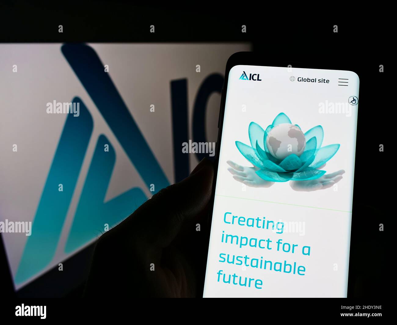 Person holding cellphone with website of Israeli chemical company ICL ...