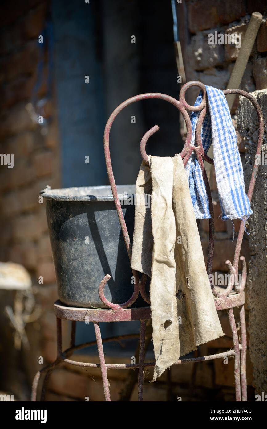 A dirty cloth hangs on an old steel armchair and there is a bucket ...