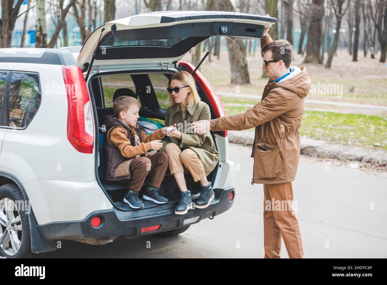 young family packing for car travel. putting bags into trunk. road trip ...