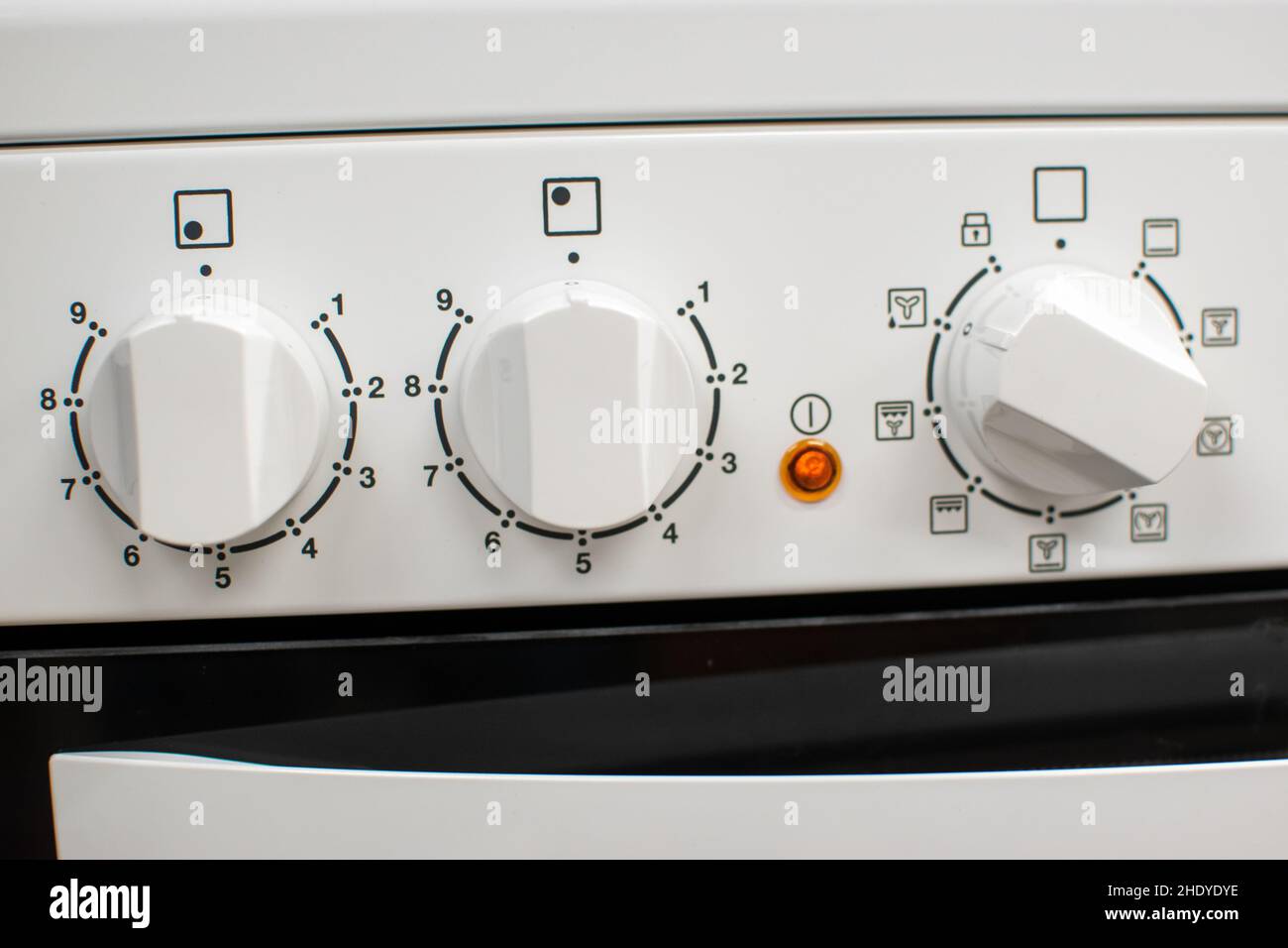 Close-up shot of a white electric cooker's front panel with multiple ...