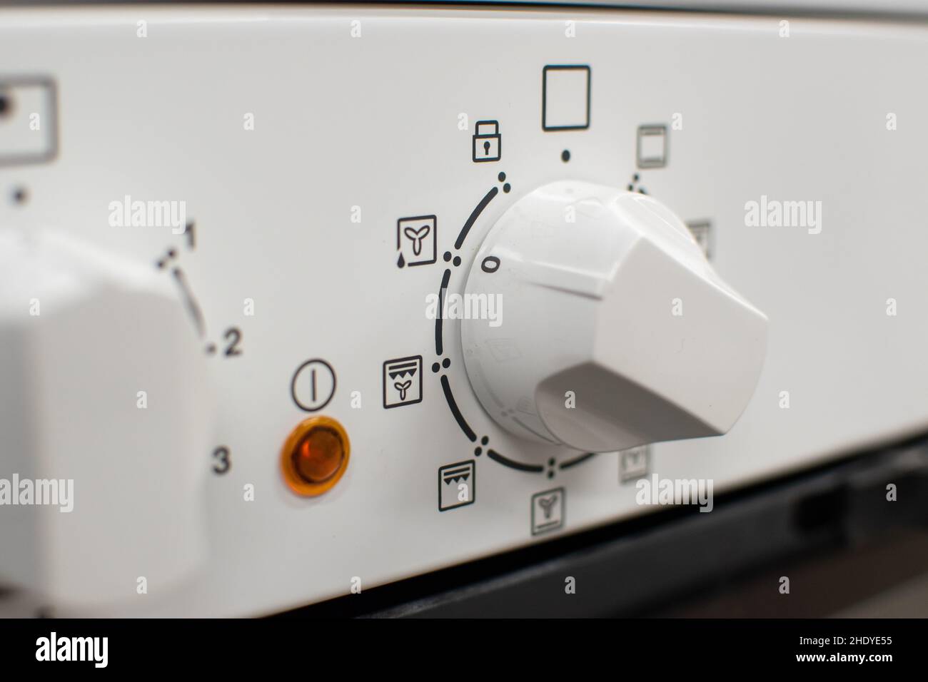 Close-up shot of a white electric cooker's front panel with multiple ...