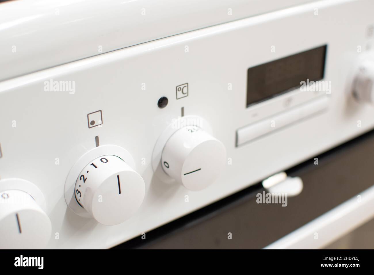 Close-up shot of a white electric cooker's front panel with multiple ...
