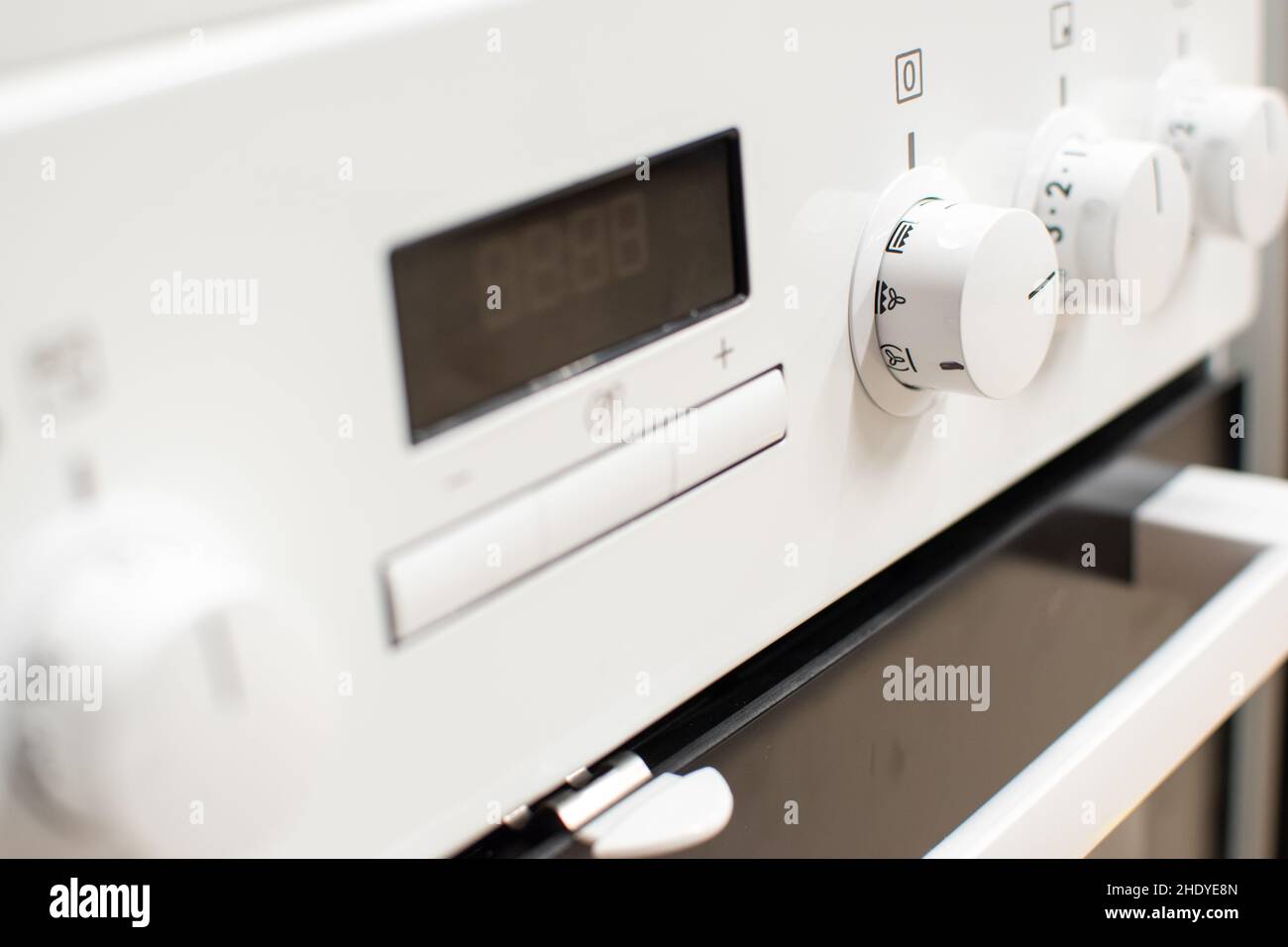 Close-up shot of a white electric cooker's front panel with multiple ...