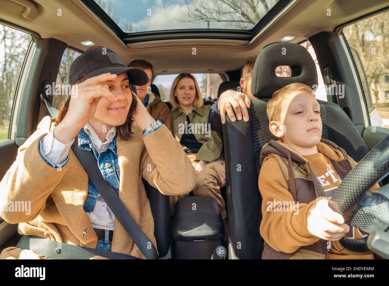 car travel fun concept. little boy driving car with adults people ...