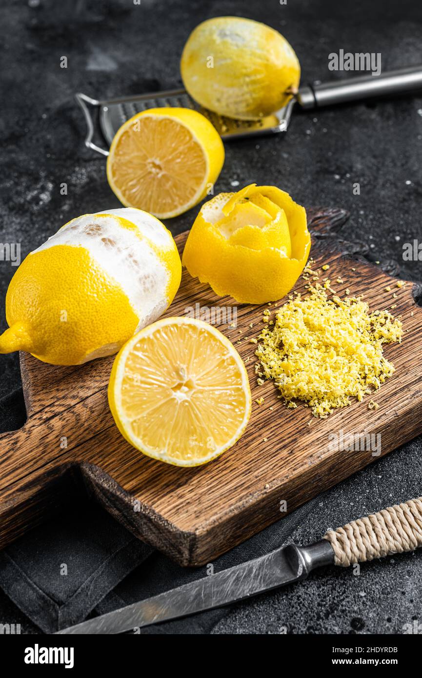 Grated Lemon Zest and spiral peel on wooden board. Black background ...