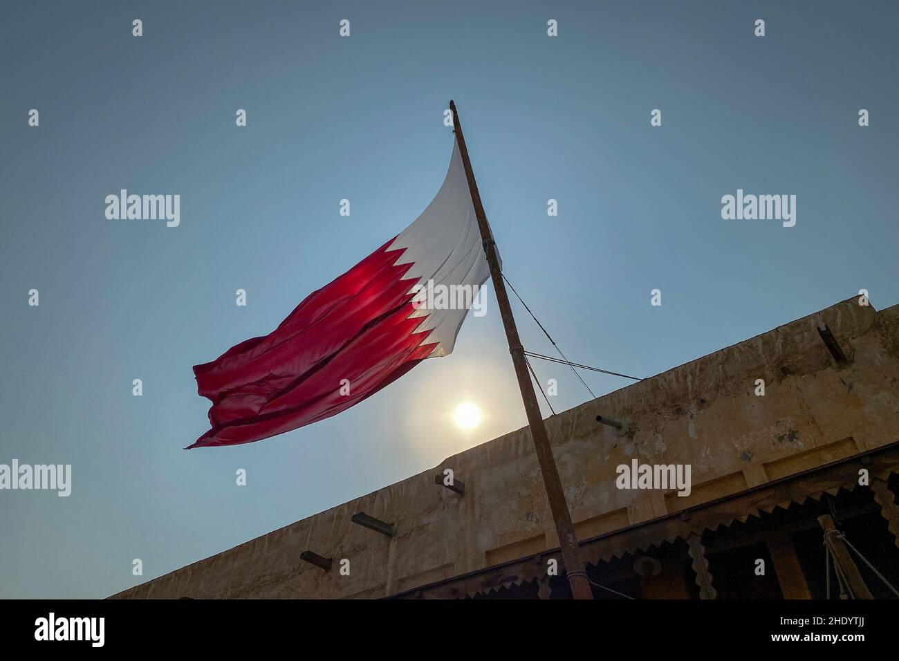 Qatari flag at a building against blue sky Stock Photo - Alamy