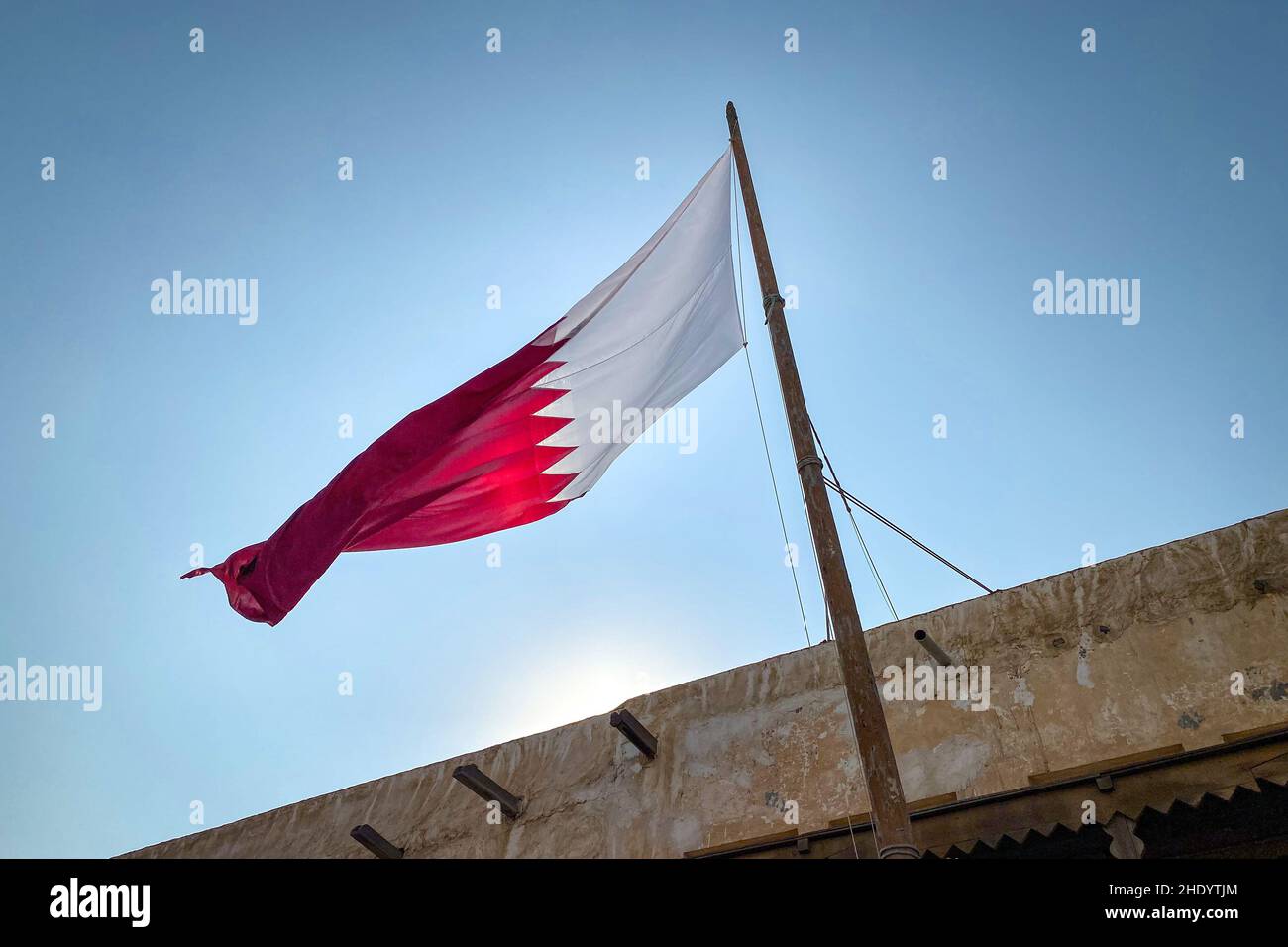 Qatari flag at a building against blue sky Stock Photo - Alamy