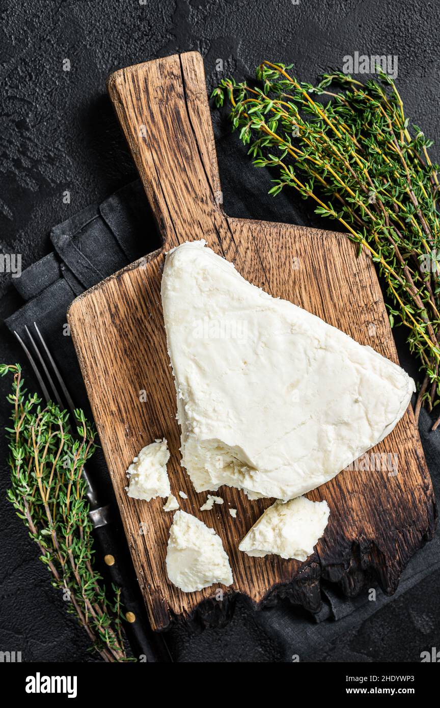 Fresh Soft goat cheese on a cutting board with thyme. Black background ...