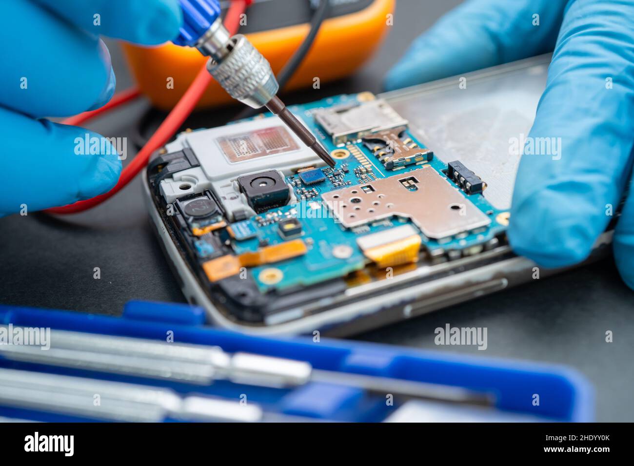 Technician repairing inside of mobile phone by soldering iron ...