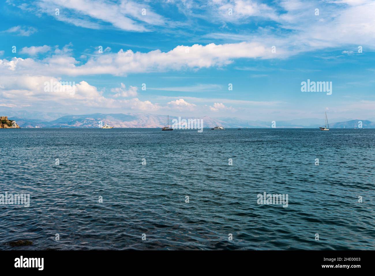 Yachts with deflated sails drift on calm sea water under blue sky with ...