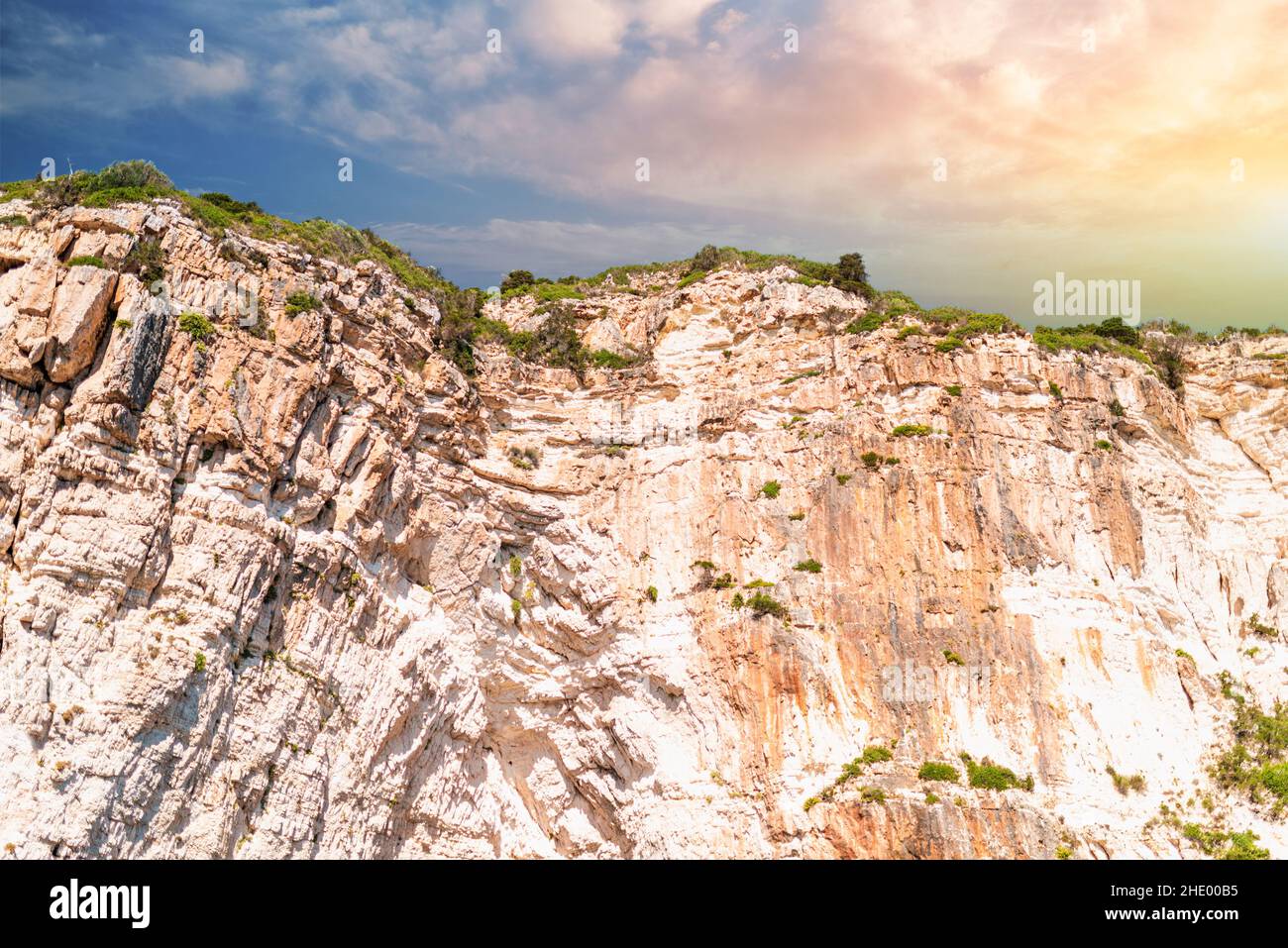 High layered light-colored stoned rocky cliffs covered with plants on ...