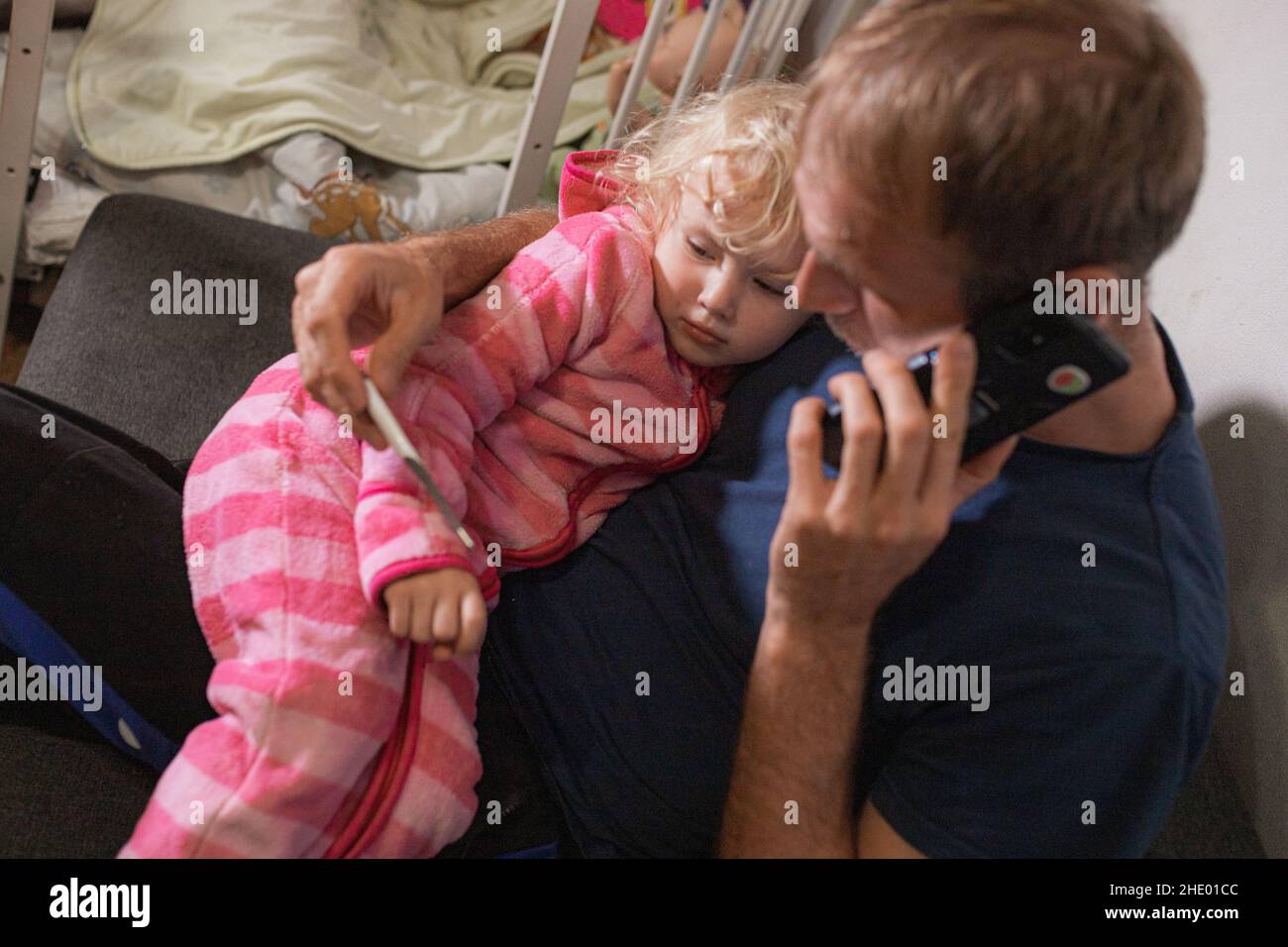 Sick little girl in arms of dad, father holds thermometer and calls ...