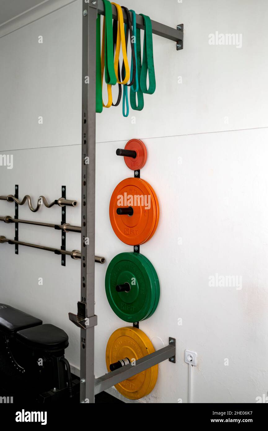 Vertical of colorful training slings hanging above barbells on a wall ...