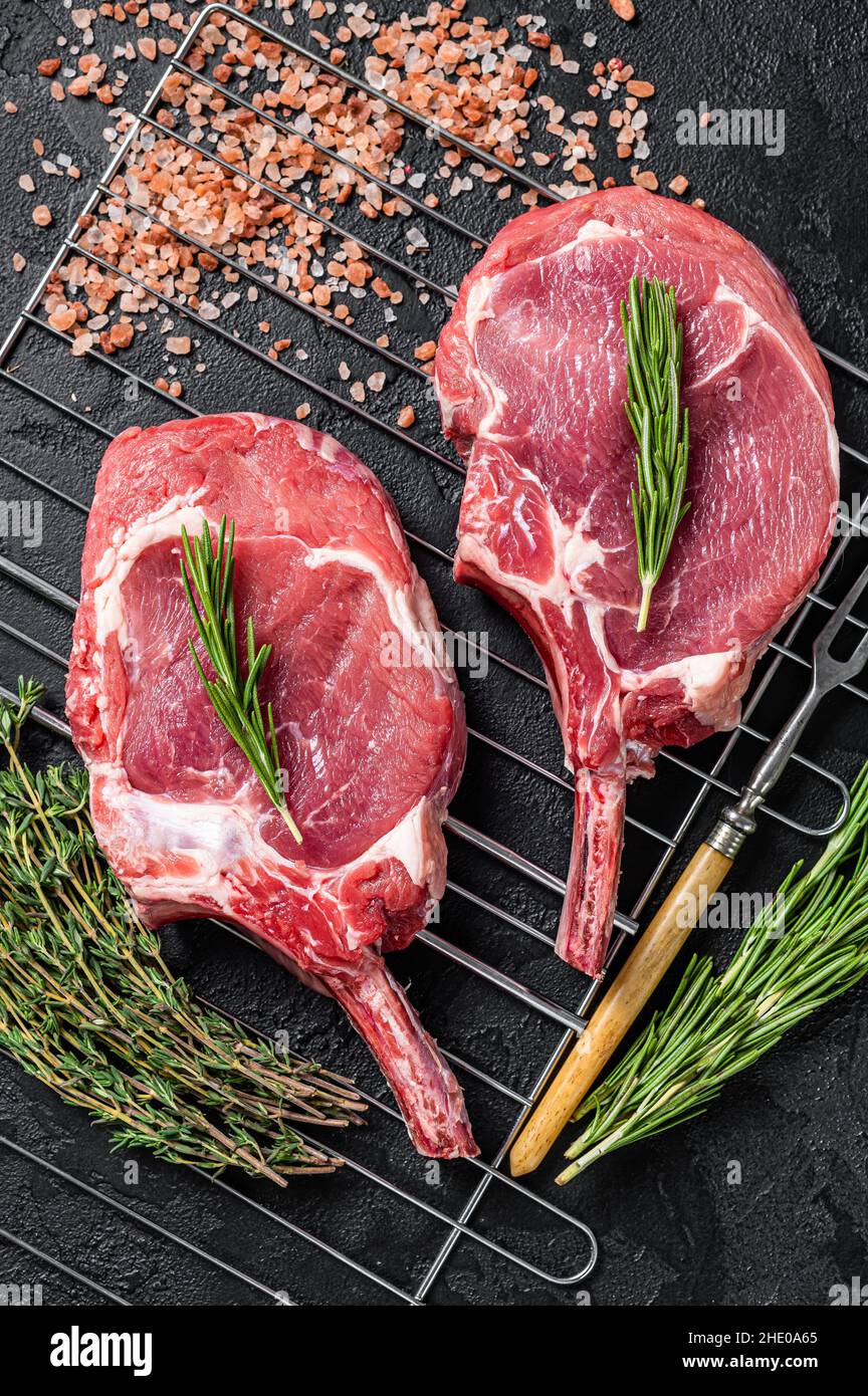 Fresh Raw Tomahawk rib eye beef steaks on grill. Black background. Top ...