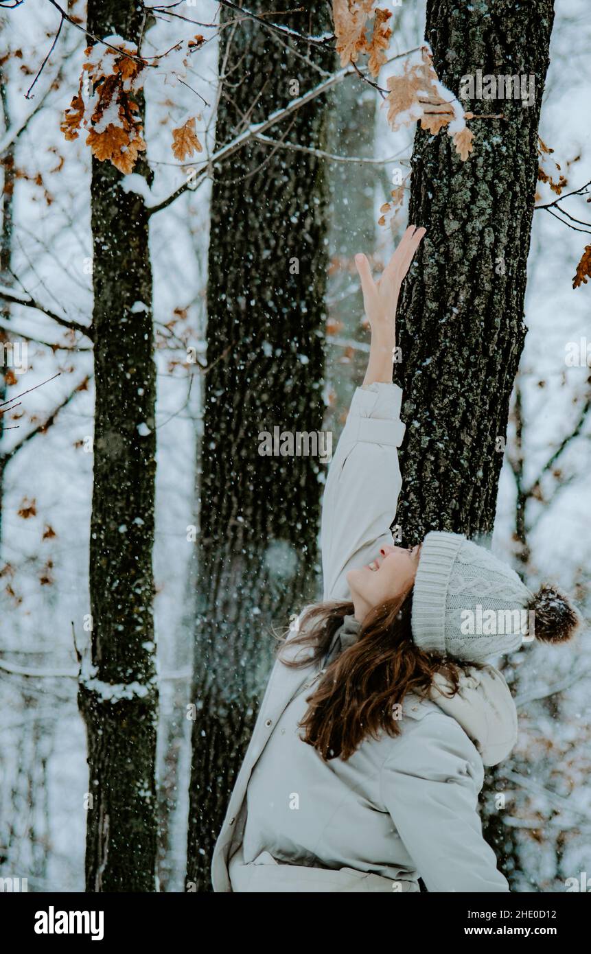 Portrait of a woman enjoying gentle snowfall in winter forest ...