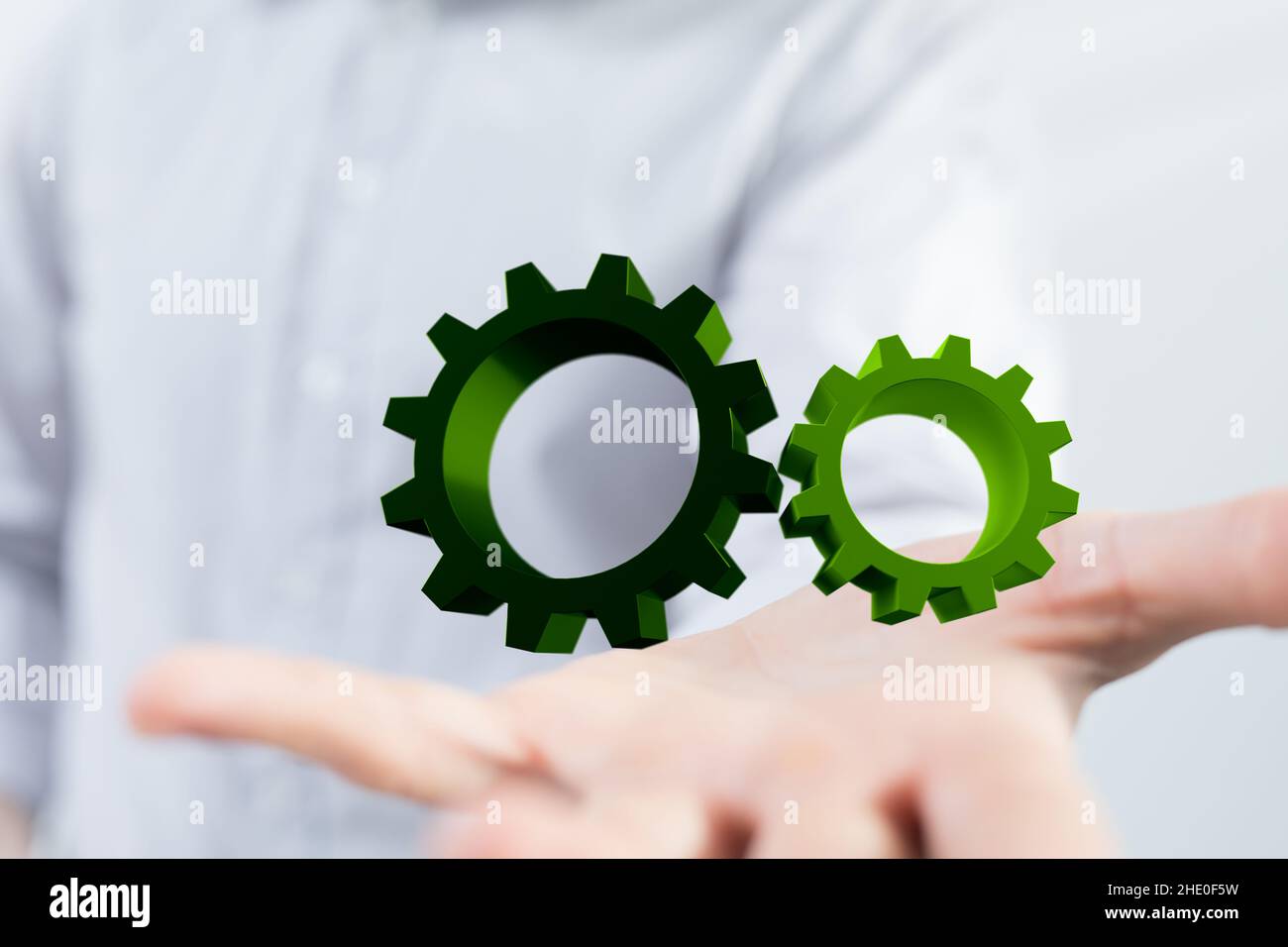 Closeup shot of a man showing a mechanism of green gears and cogs at ...