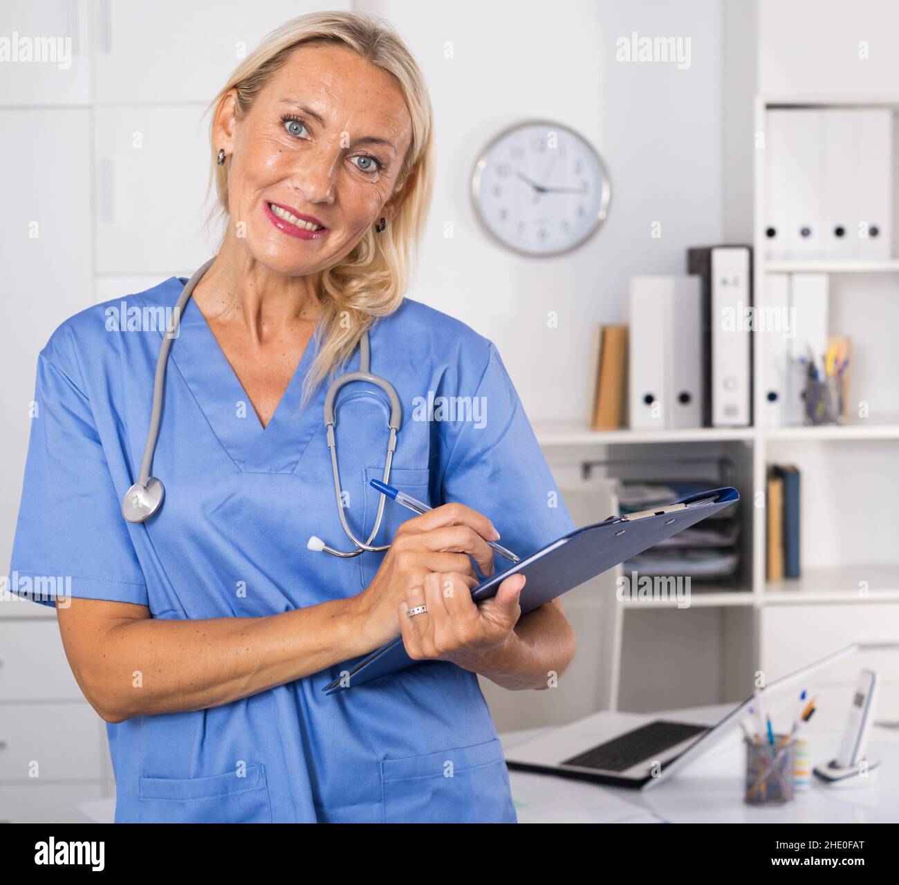Female doctor writing notes on clipboard in clinic Stock Photo - Alamy