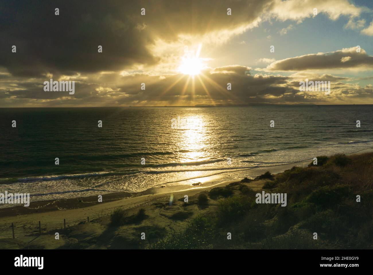 Sunset over ocean as seen from cliff with sandy beach below Stock Photo ...
