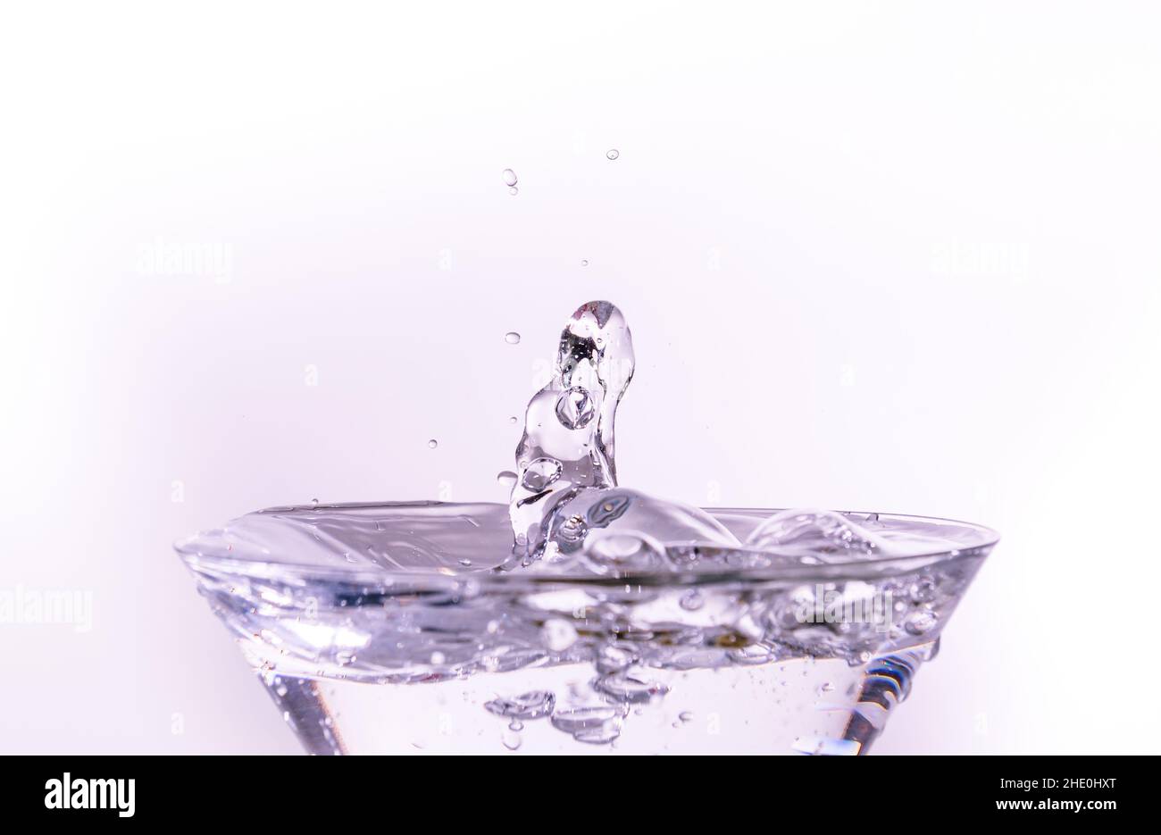 Drop of water falling on filled glass making an isolated splash with a ...