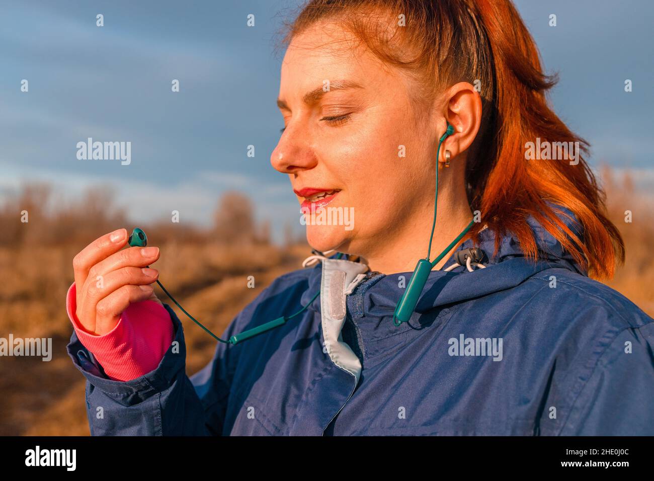 Young girl athlete wears sports headphones for running on a sunny ...