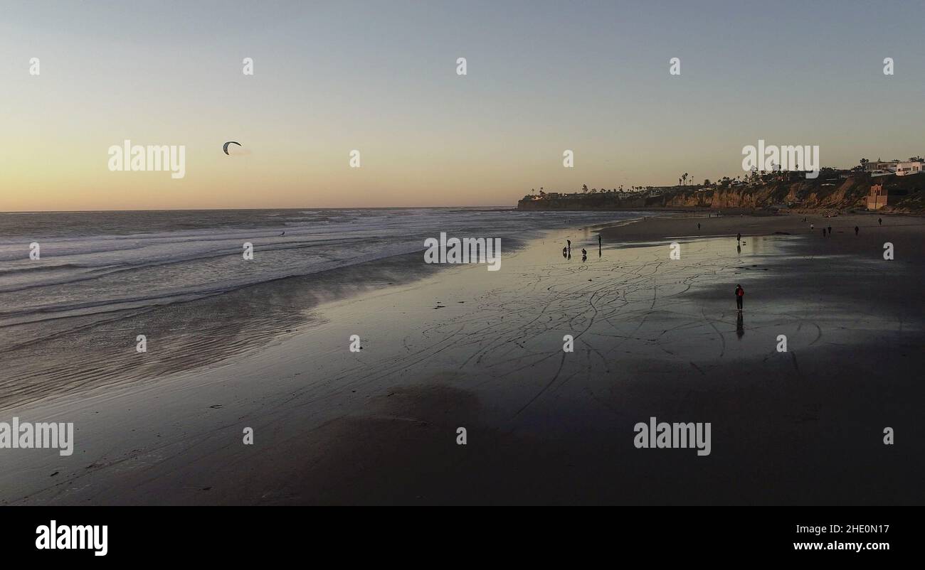 People walking and jogging on wide, expansive Pacific Beach at low tide ...