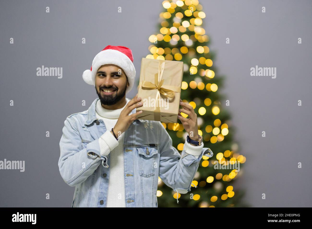 Curious Santa man sitting in front of Christmas tree background ...