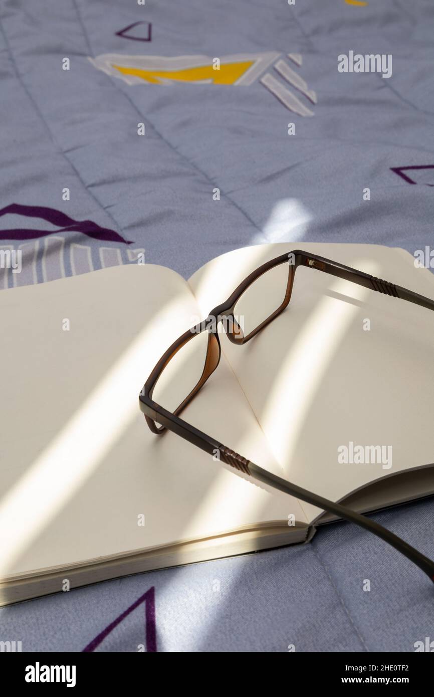 open notebook, detail in its blank sheets, on top of glasses for ...