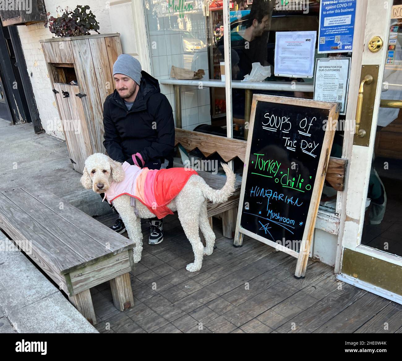 Man sits outside a cafe with his dog in the morning on 7th Avenue in ...