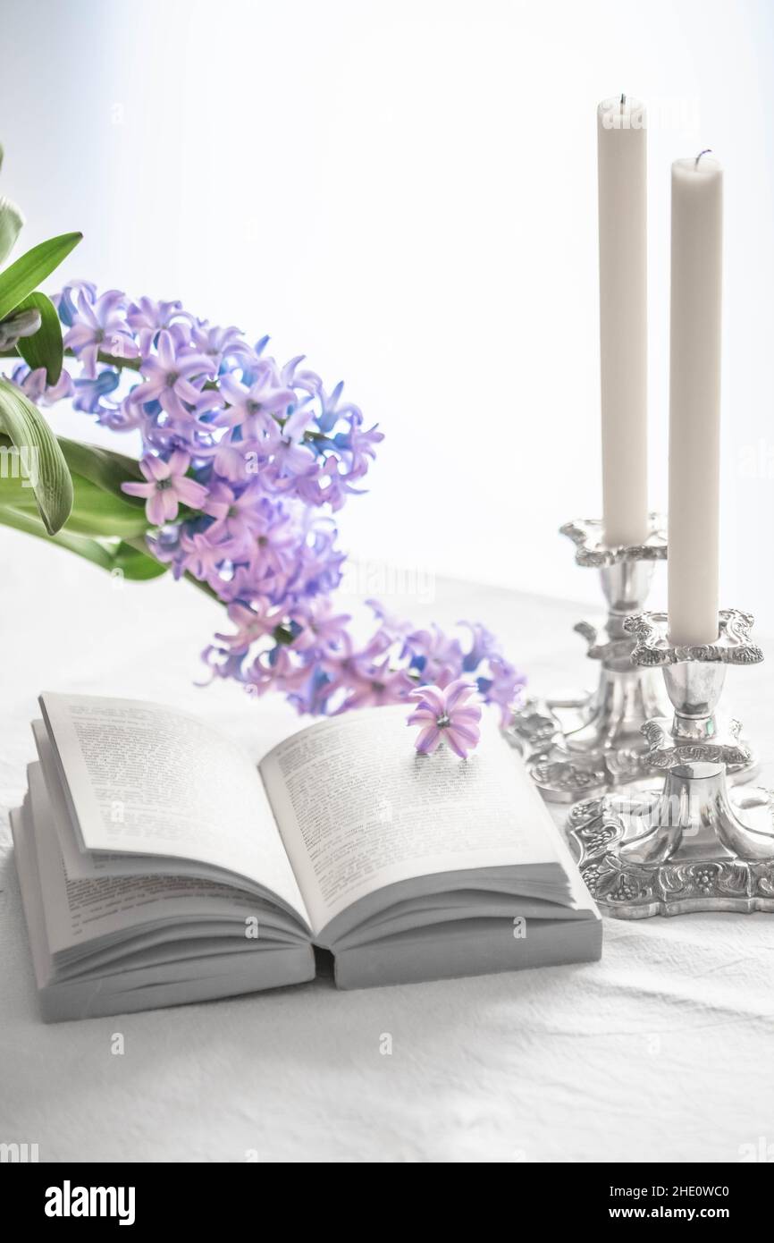 open book and two candles on a table with spring flowers Stock Photo ...