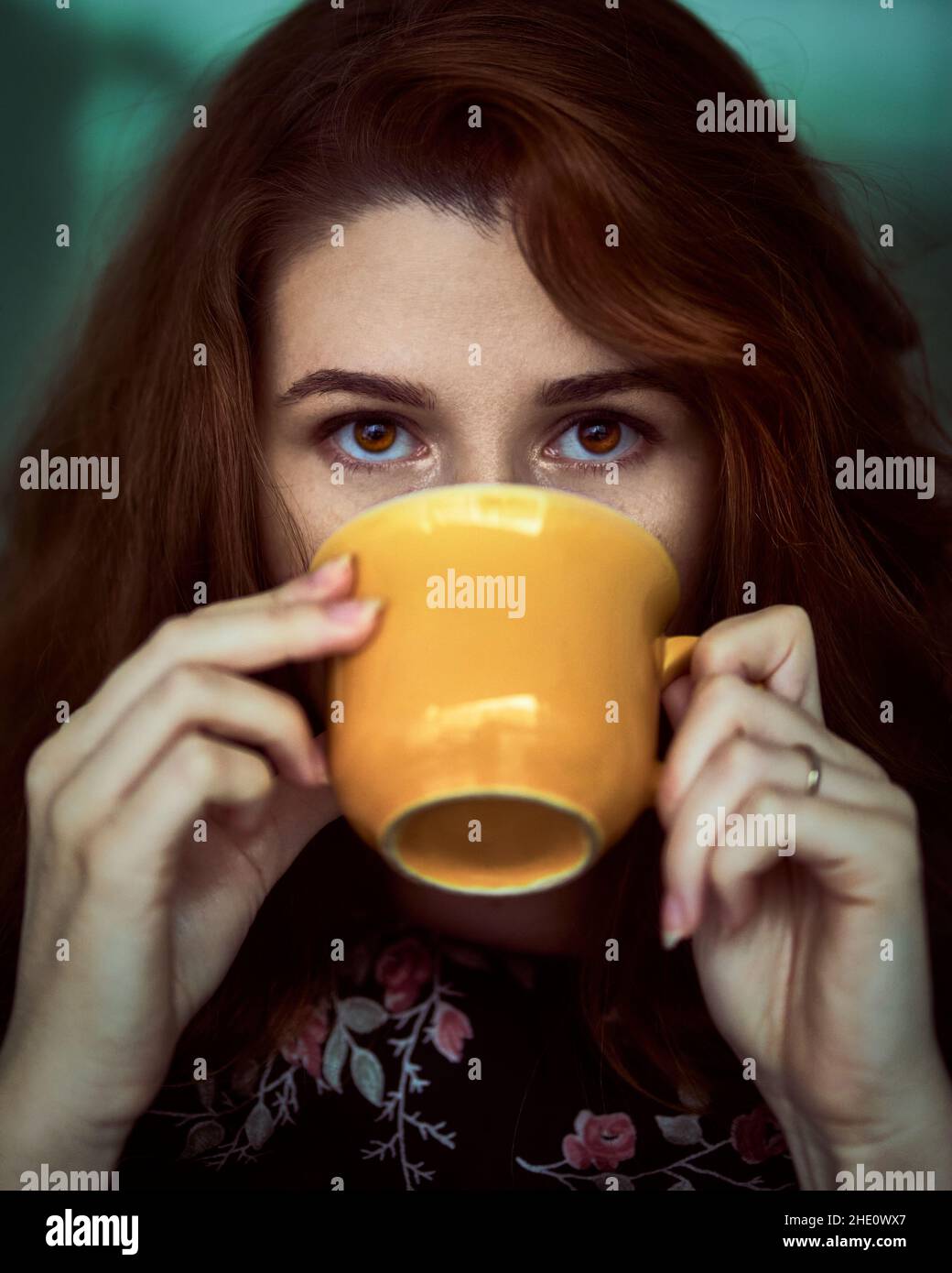 Closeup of Caucasian female drinking from a yellow cup while looking at ...