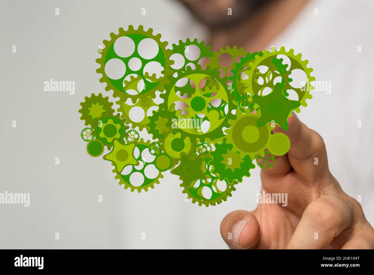 Male's hand holding an illustration of green metallic gears and cogs ...