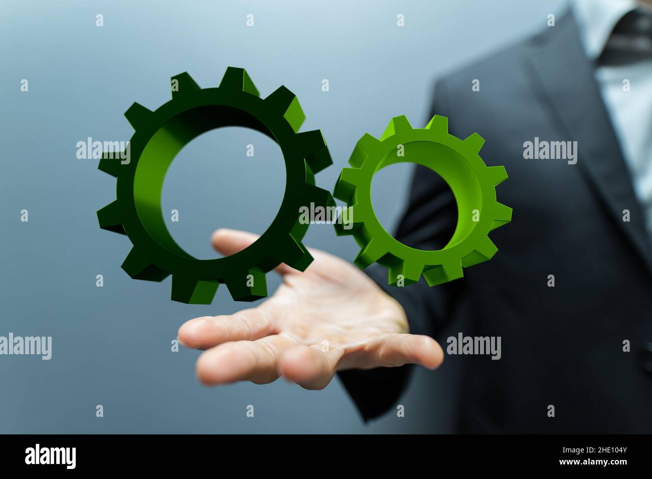 Male's hand holding an illustration of green metallic gears and cogs ...