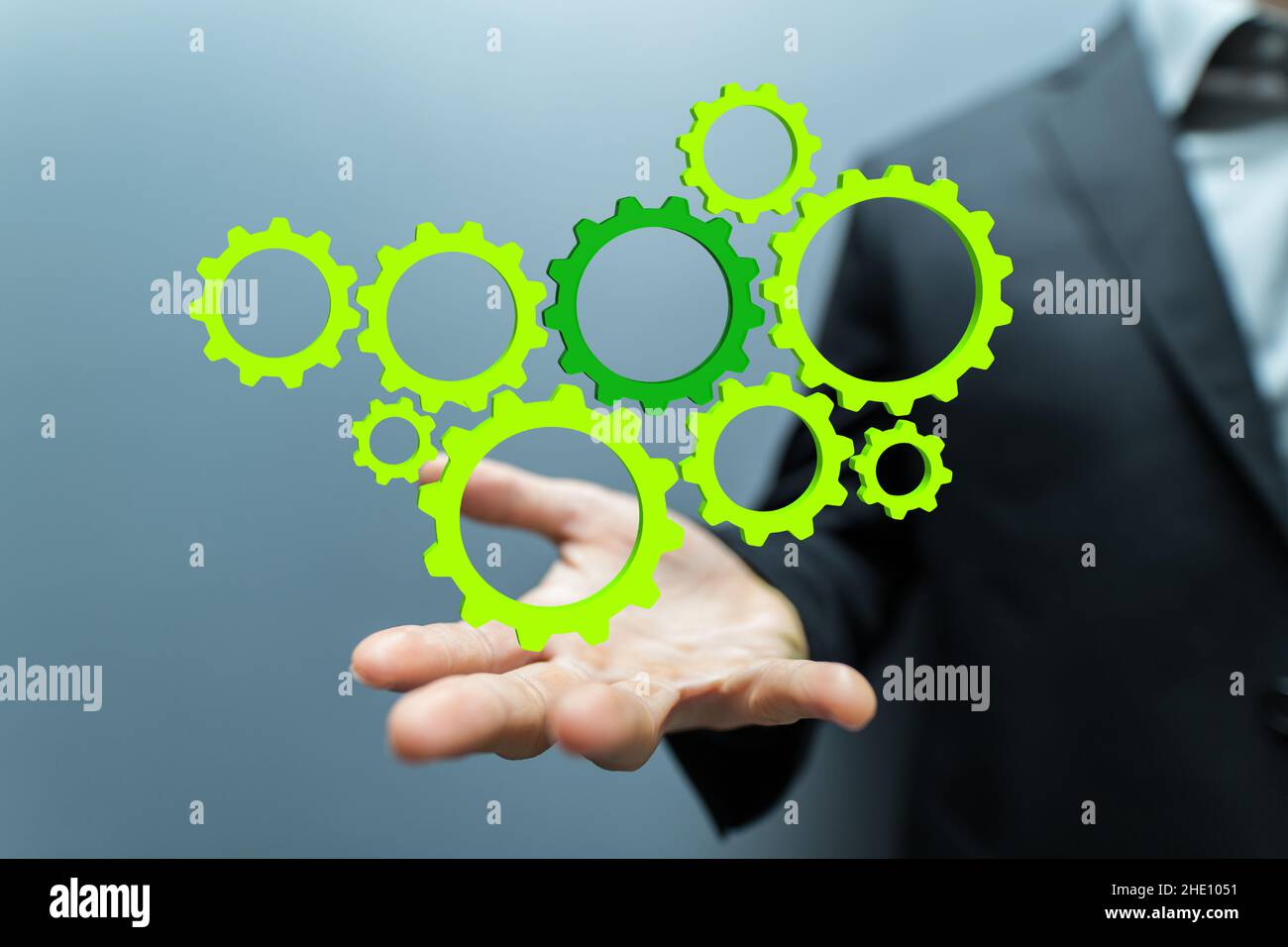 Male's hand holding an illustration of green metallic gears and cogs ...