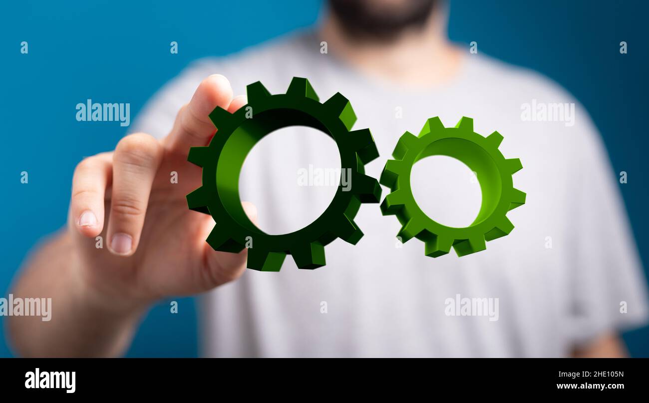 Male's hand holding an illustration of green metallic gears and cogs ...