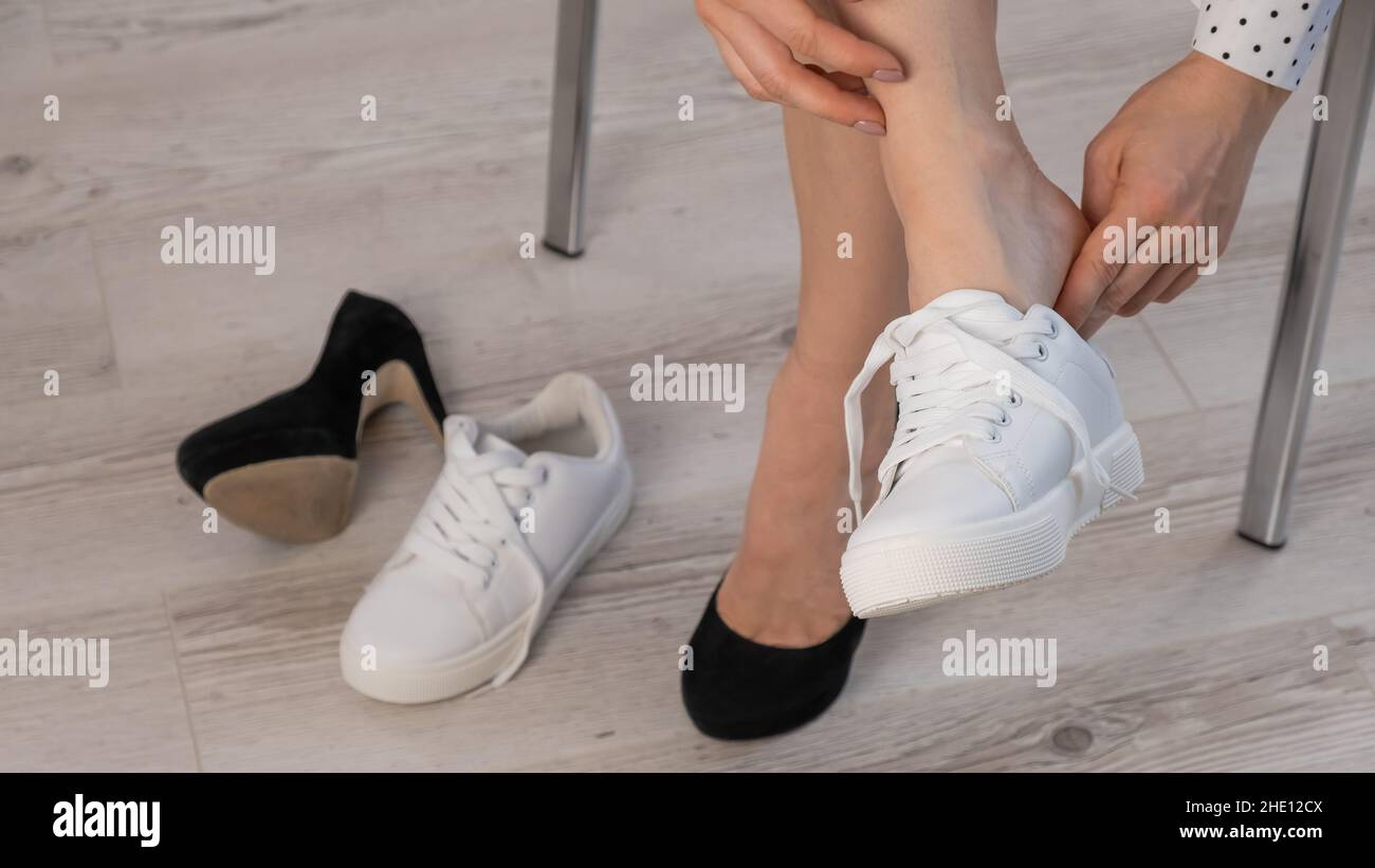 Close-up business woman takes off her shoes puts on white leather ...