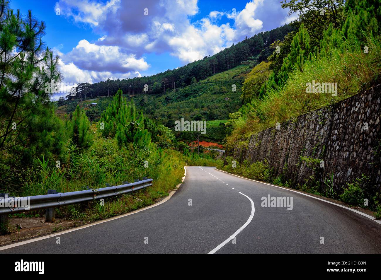 A curve in the two lane road with most in light shadow except for a ...