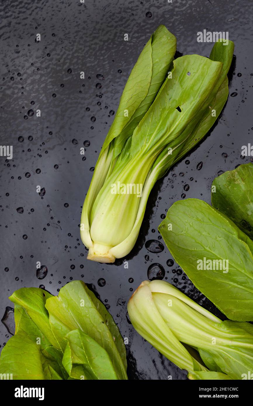 Freshly washed raw Bok choy on black table with water droplets Stock ...