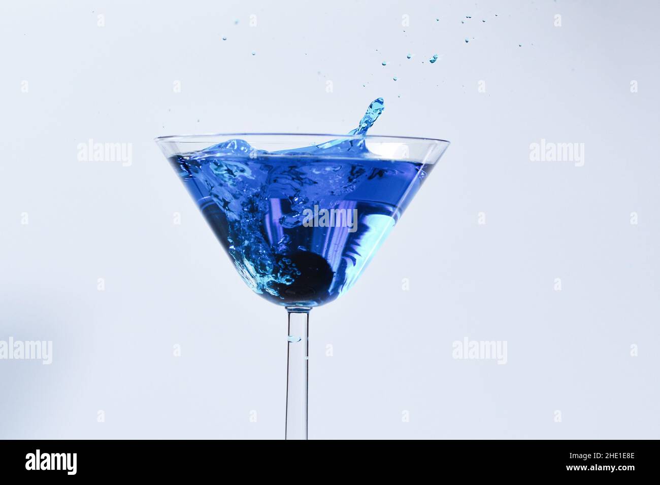 Cocktail with blue liquid in glass. Glass with blue water pouring with ...