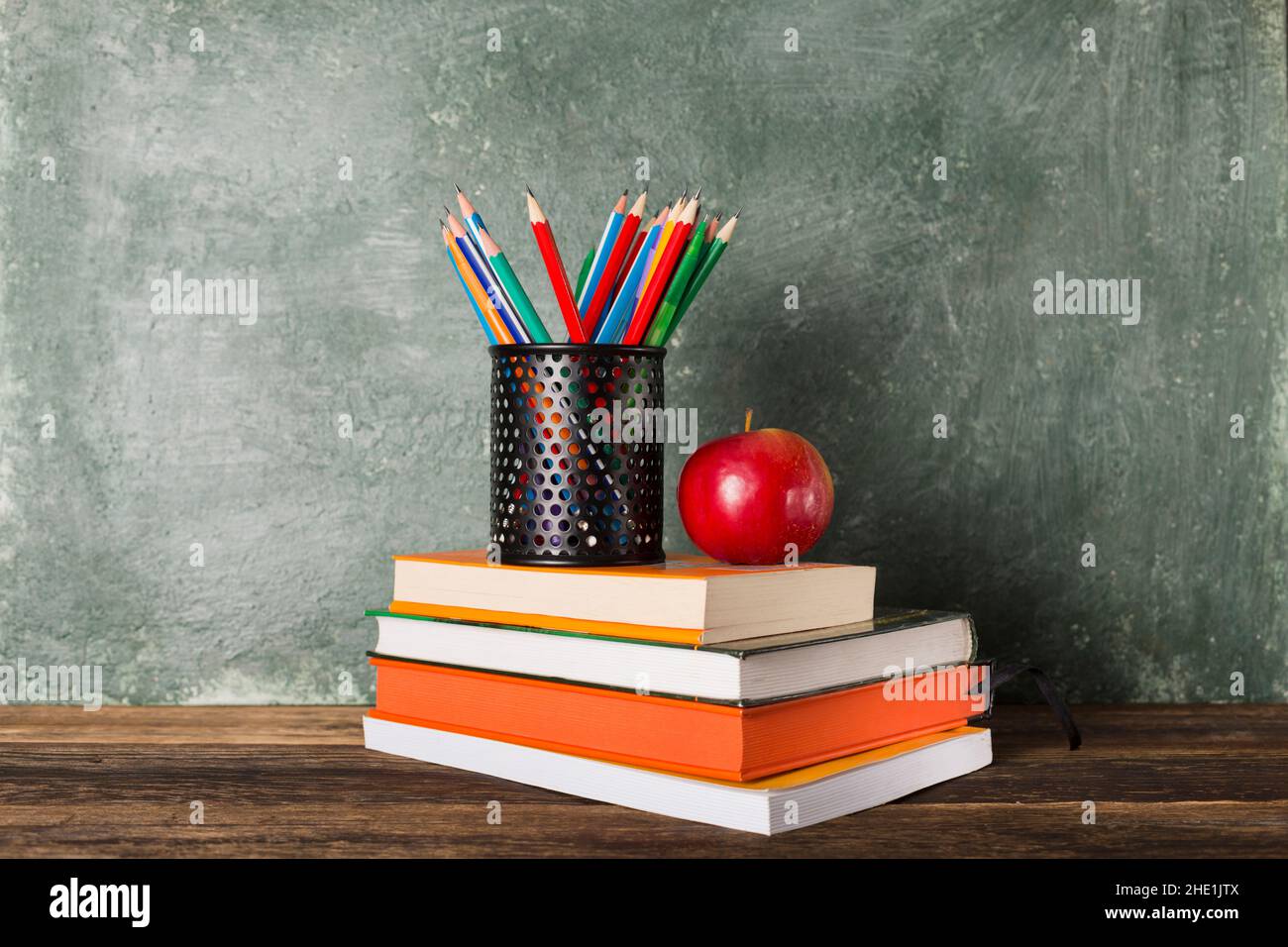a Stack of books and stationery and a red apple on the background of ...