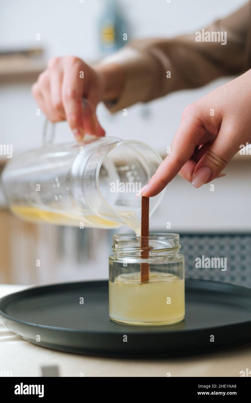 Close-up vertical shot of unrecognizable female artisan pouring melted ...