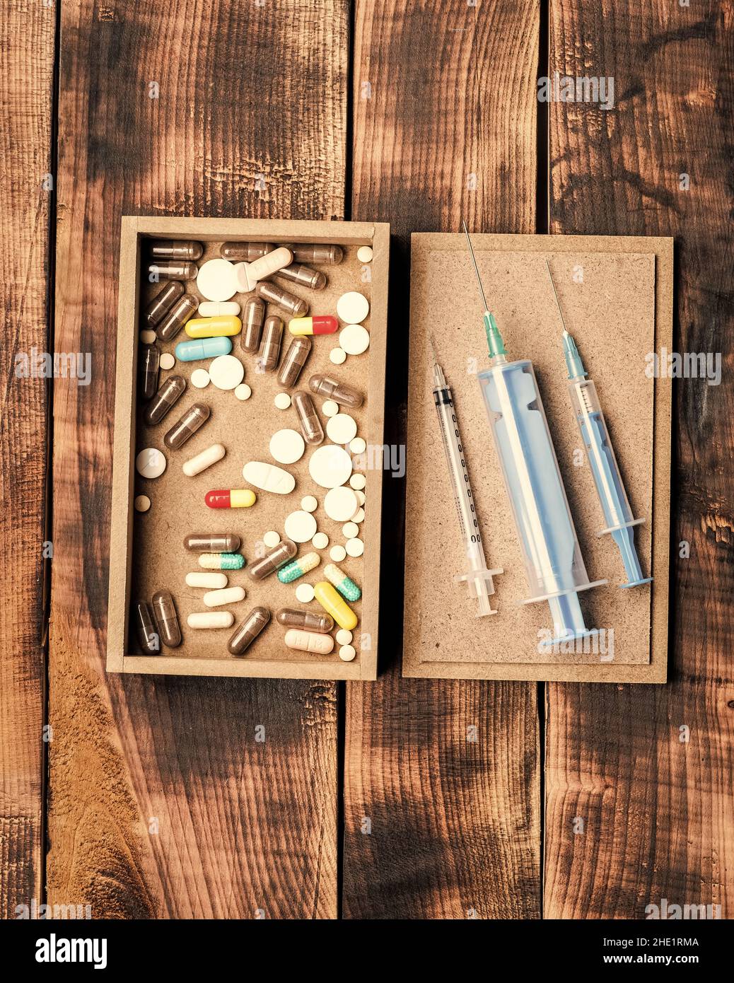 Pharmaceutical drugs pills and syringe vials in box on wooden ...