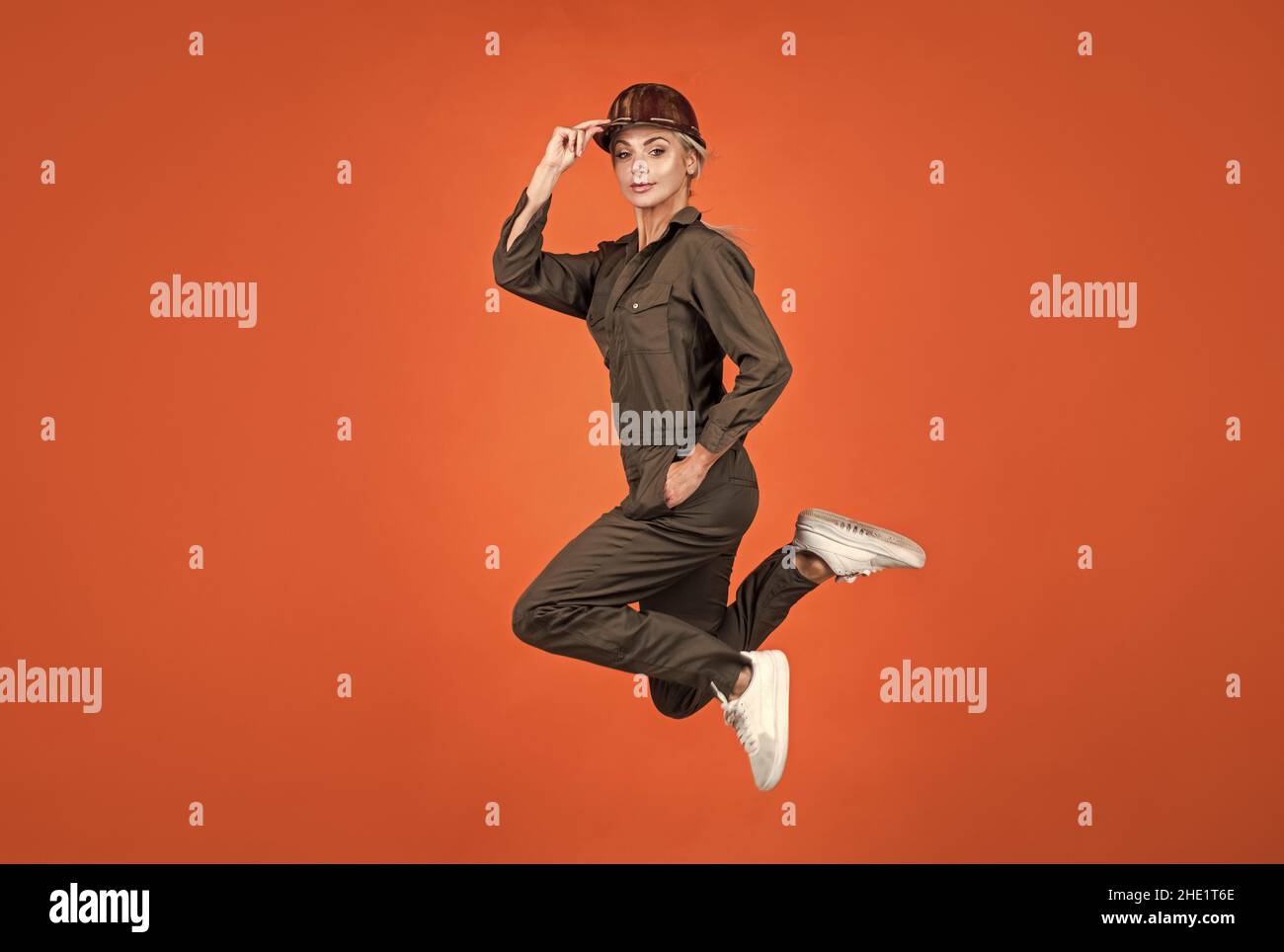 jumping woman in working uniform and hard hat running hurry up on work ...