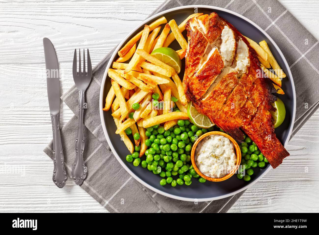roast Atlantic redfish on a plate with french fries, boiled green peas ...
