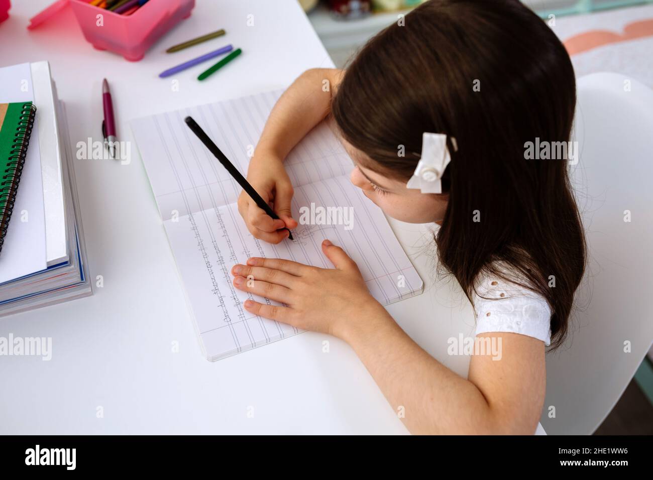 Girl doing homework sitting at a desk Stock Photo - Alamy